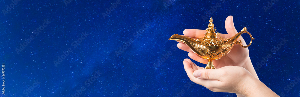 Rubbing magic lamp with female hands against night blue sky with stars ...