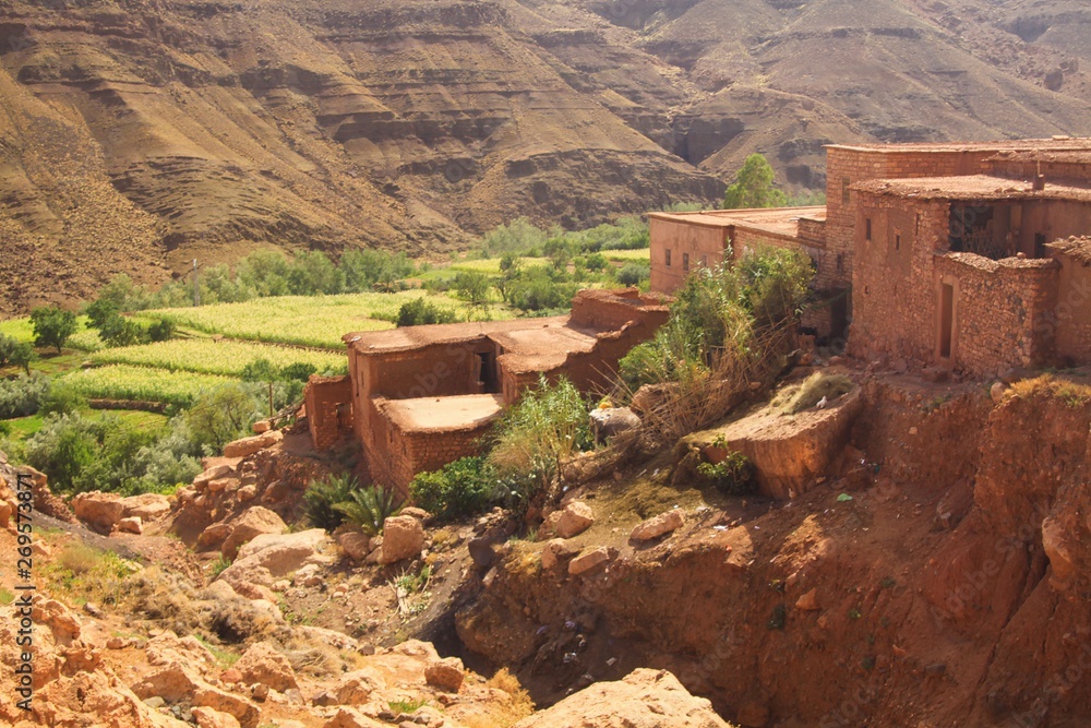 Berber village in valley surrounded by rugged high mountain walls with ...