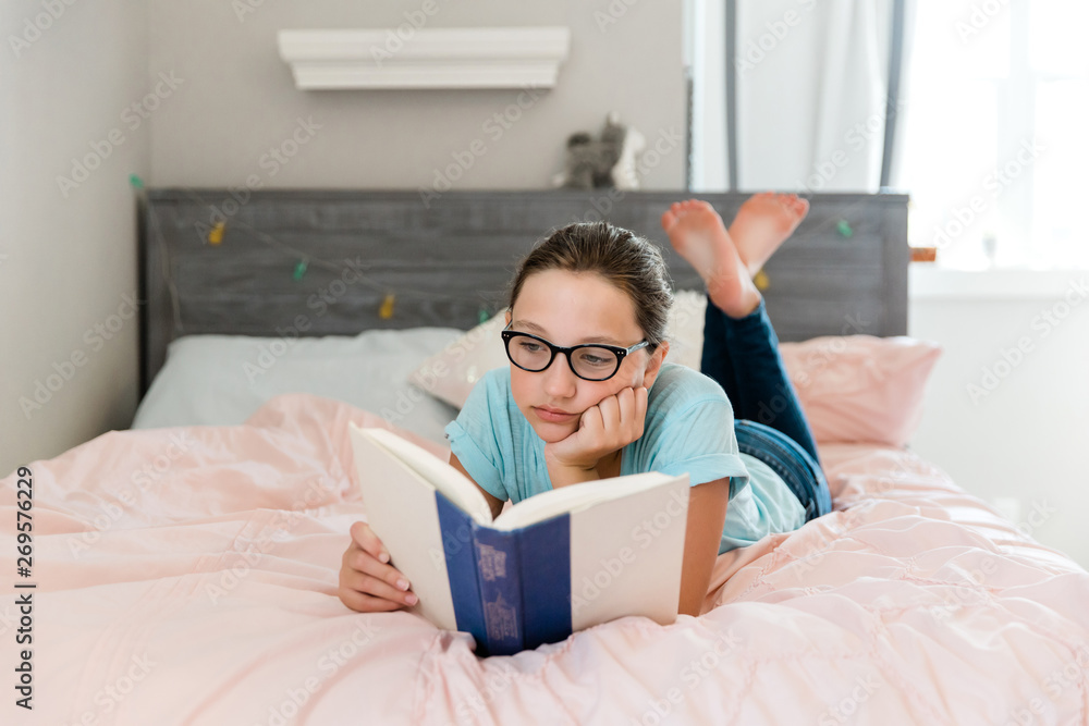 Tween Teen Girl With Glasses Quietly Reading a Book in her bedroom on ...