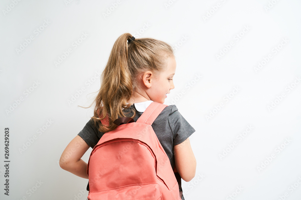 Back view of little girl photographed against white background wearing ...