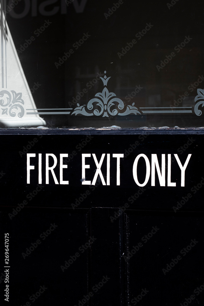 emergency fire exit only sign on black painted timber door to retail ...