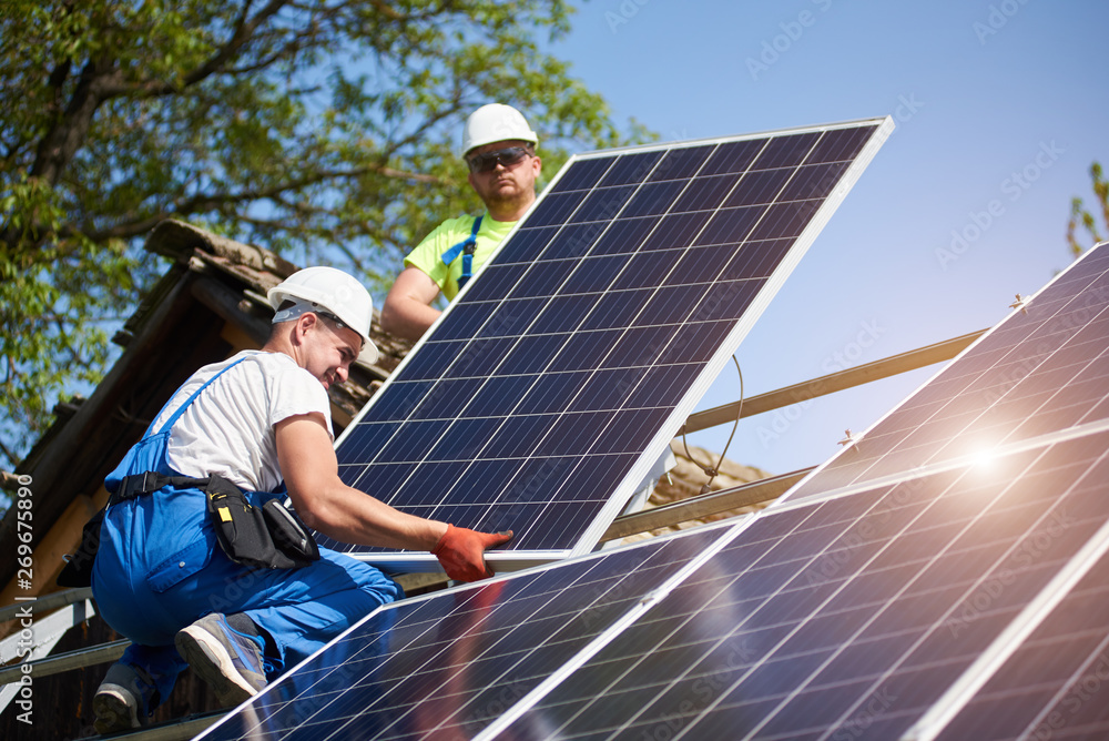 Two professional technicians adjusting heavy solar photo voltaic panels ...