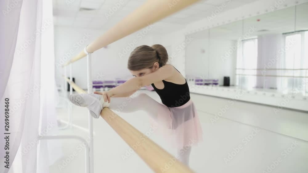 Little girls using ballet barre when doing leg stretching exercises in ...