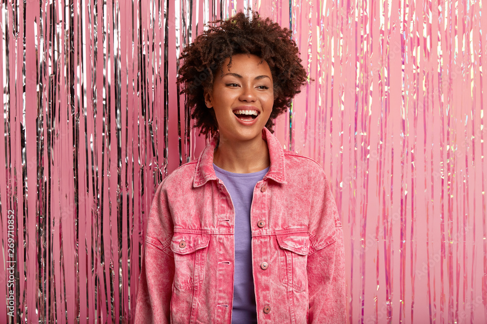 Young smiling African American female has minimal make up, wears pink ...