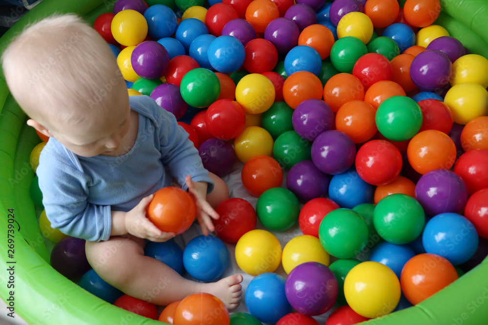 One year old baby boy is playing in ball pool on safety playground ...