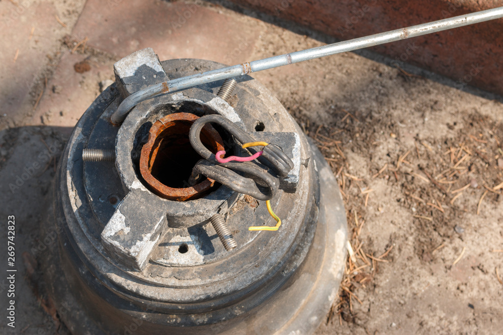 base of a broken street lamp with broken wires. Base of the light pole ...