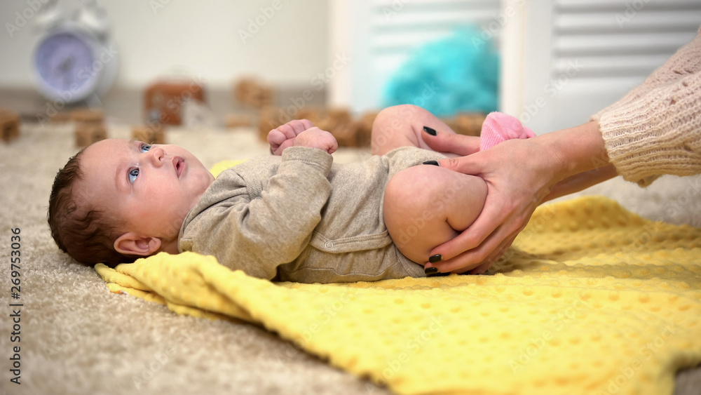 Lady massaging baby legs, thigh joints dysplasia prevention, reducing ...