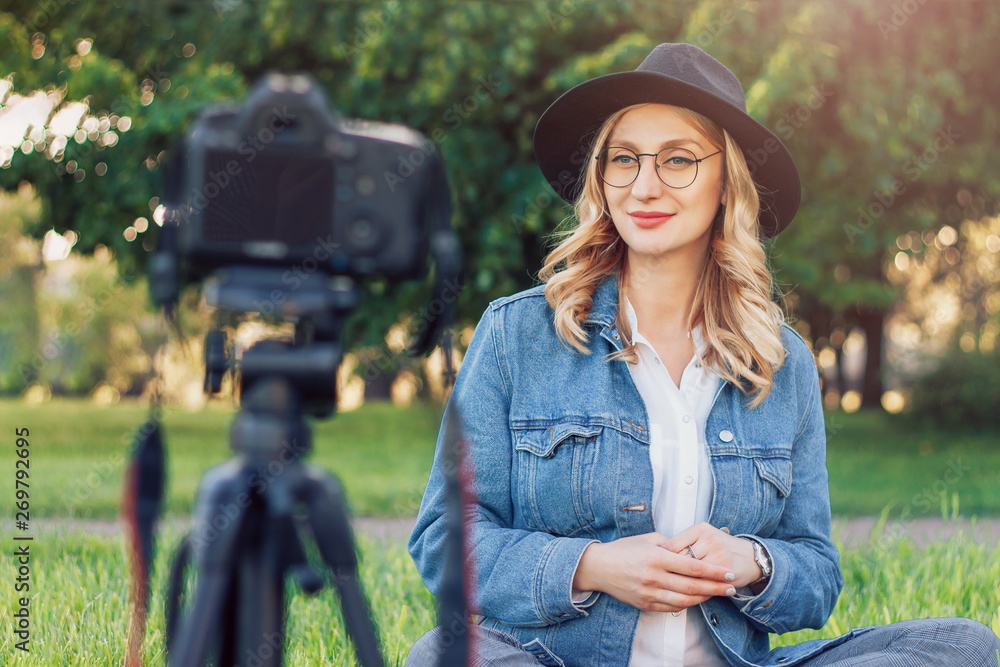 Stylish young girl blogger sitting on the street on the grass and ...