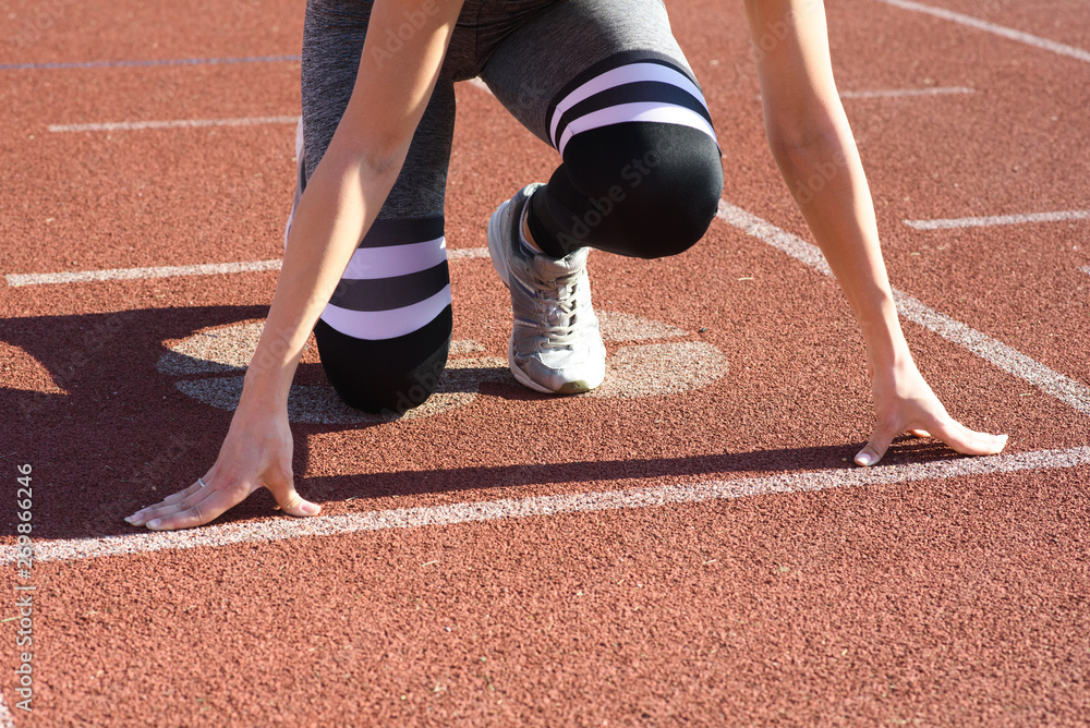 Young beautiful woman runner outdoor standing in start pose at the ...