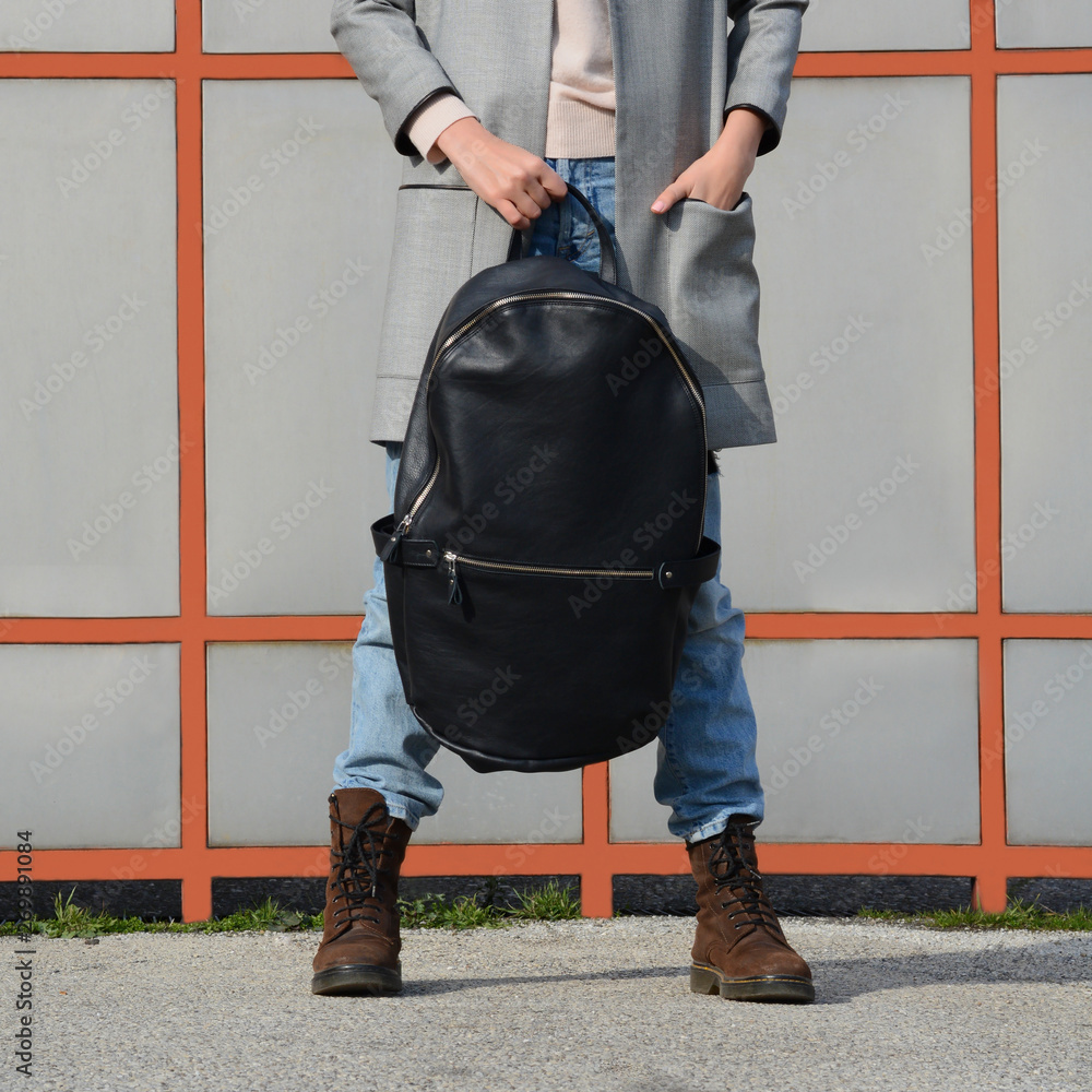 Girl in blue jeans, brown boots and a gray blazer holding a big black ...