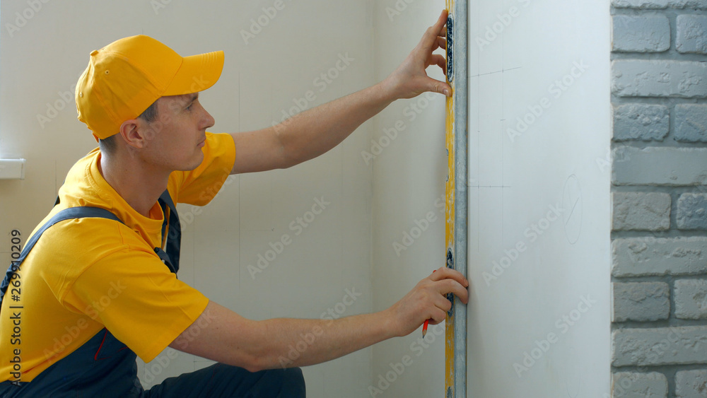 Repairman making measurement of wall. Young caucasian builder measuring ...