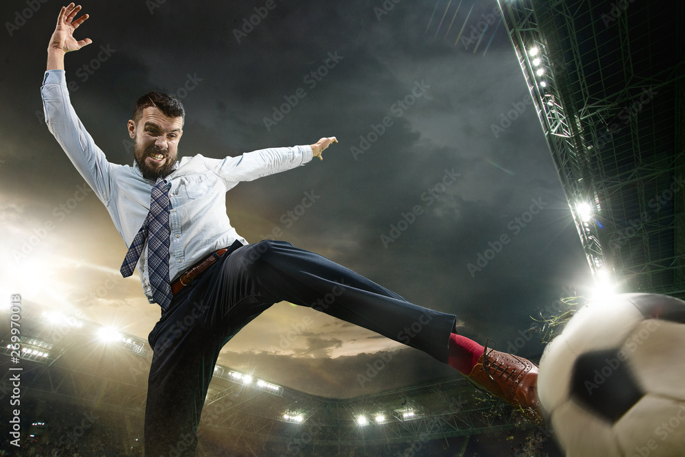 Office man as a soccer or football player at the stadium. Kicking a ...