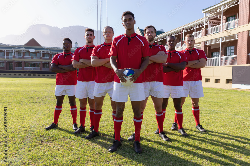 Team of male rugby players standing with rugby ball in the rugby ground ...