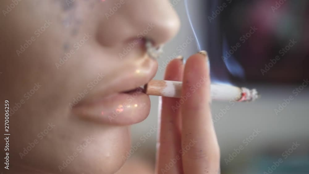 Close up of woman smoking cigarette. Lady with nose ring puts cigarette ...