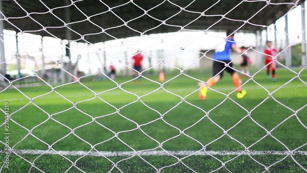 White goalposts and mesh of goal with blurry of soccer goalkeeper and ...