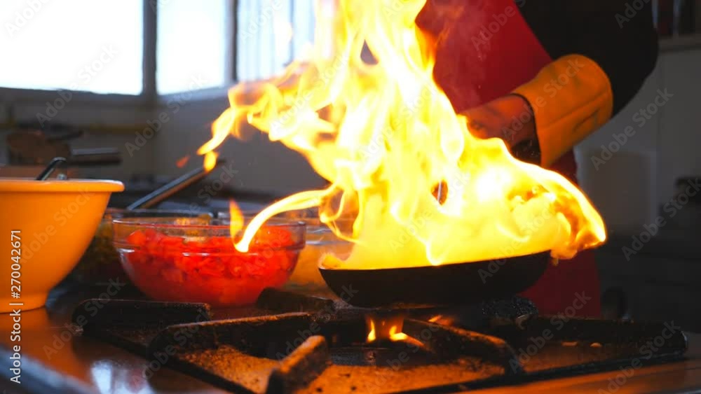 Unrecognizable chef cooking tasty flambe style dish on pan for visitors ...