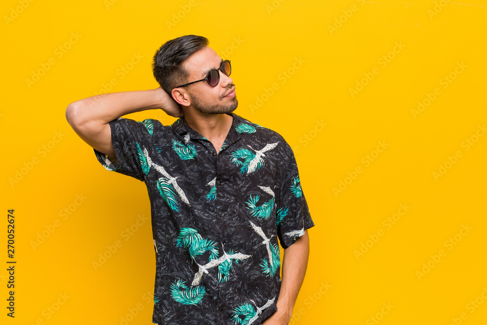 Young filipino man wearing summer clothes touching back of head ...