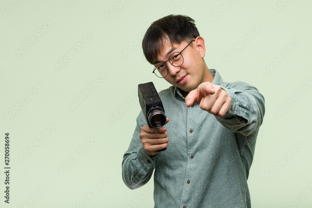 Young chinese man holding a vintage camera cheerful and smiling ...