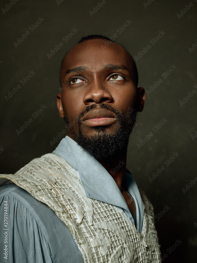Young man as a medieval grandee or nobleman on dark studio background ...