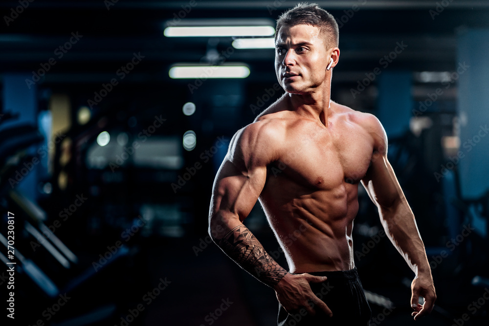 Side view of a caucasian handsome fitness model posing in the gym. Man ...
