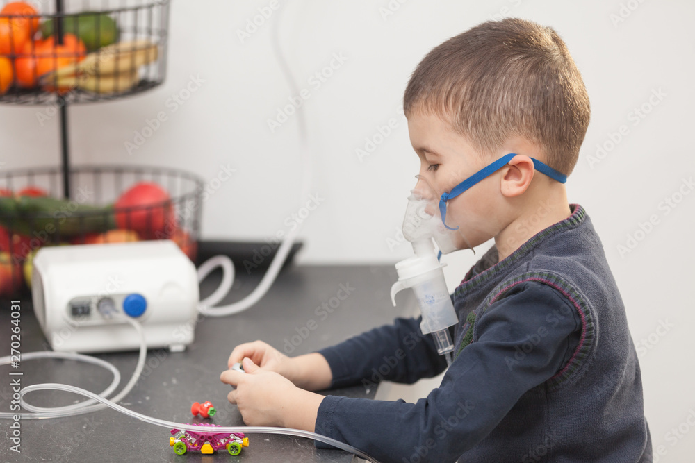 Little boy playing with toys while doing his inhalation with nebulizer ...