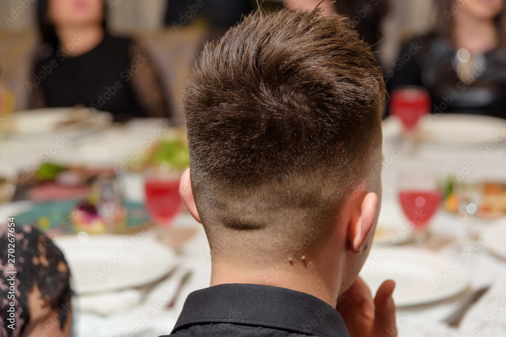 The guy with a short haircut is sitting at the table. The back of a man ...