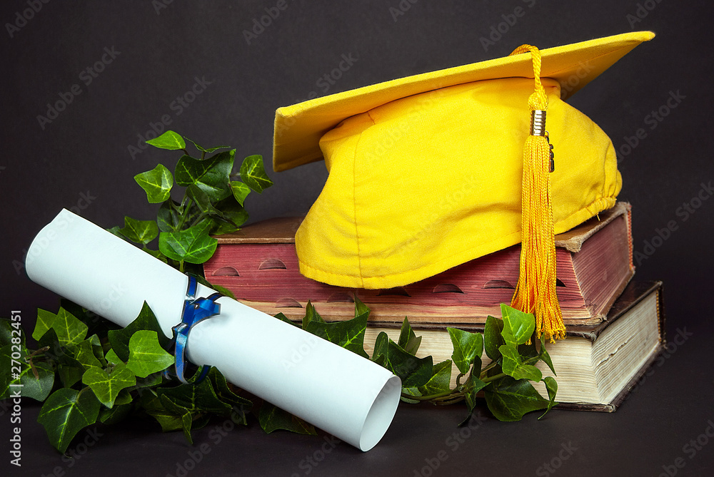 bright gold graduation cap on old books with white blank diploma tied ...