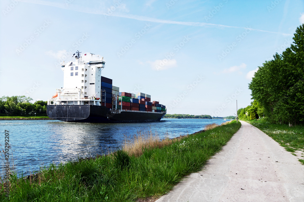 Foto de Nord-Ostsee-Kanal in Schleswig-Holstein, Containerschiff mit Radwanderweg in Rendsburg ...