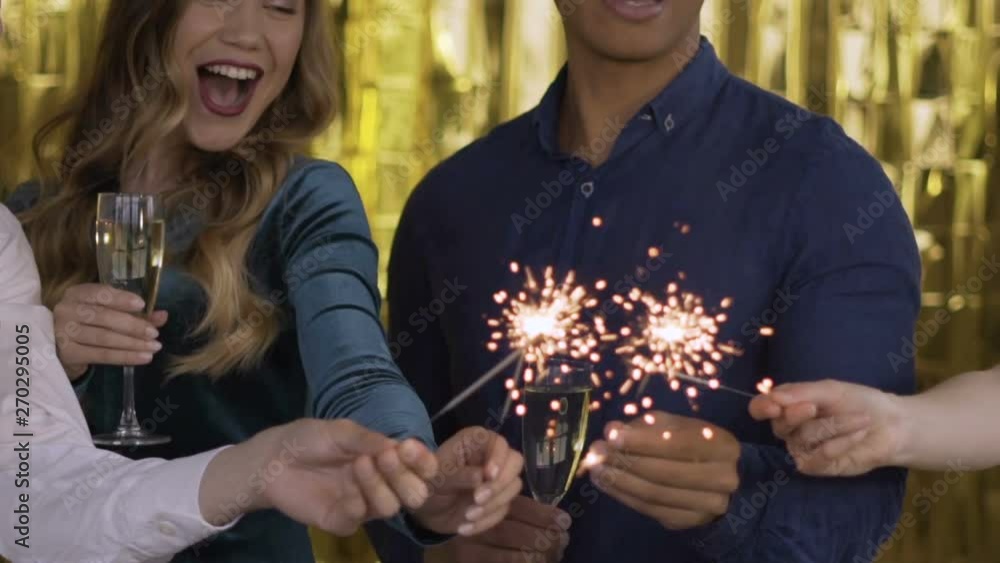 4 happy cheerful people at a party light a sparkler. a group of ...