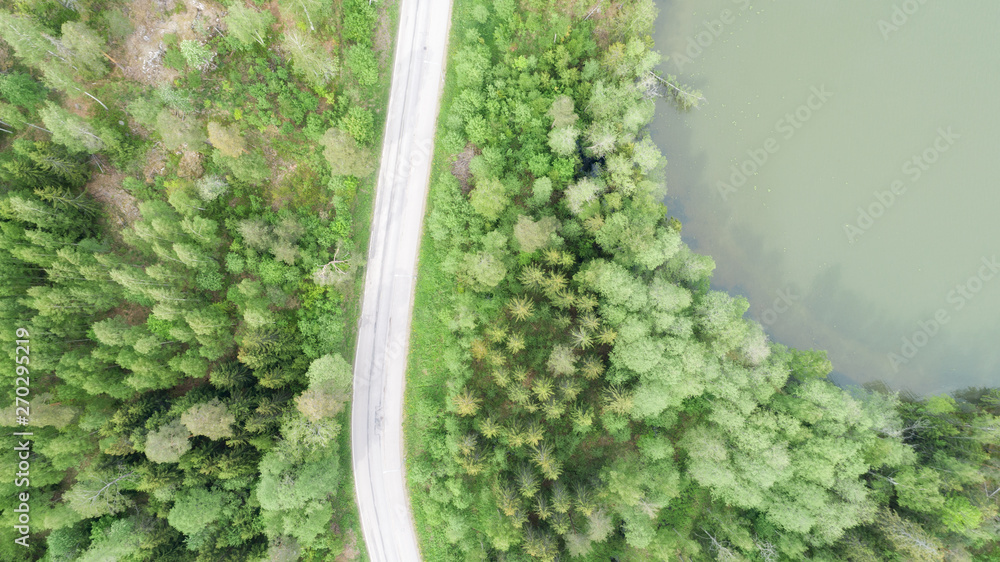 Aerial top down view of two-lane road with forest on one side, and lake ...