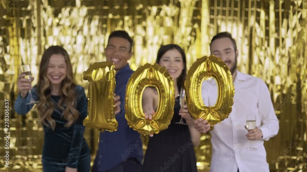 The number 100 of foil. 4 happy cheerful people at a party with ...