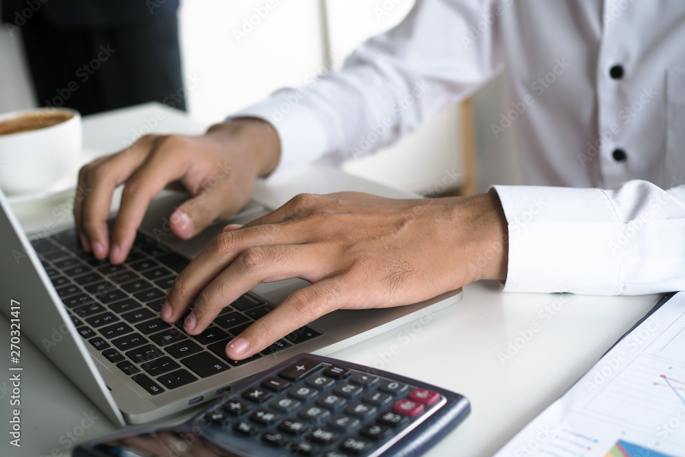 The human hand uses the keyboard by the notebook on the desk. Internet ...