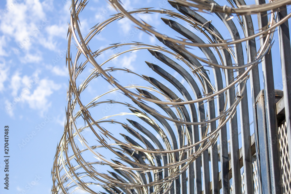 Barbed wire loops on the perimeter of a sharp metal fence Stock Photo ...