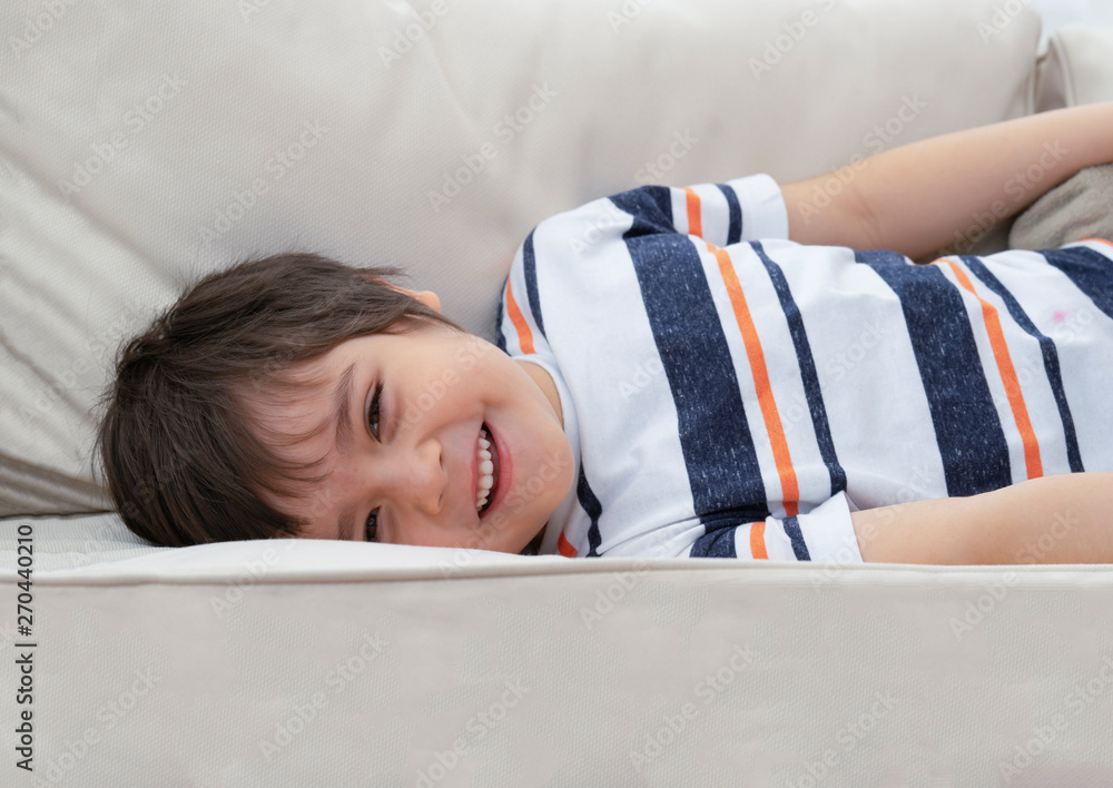 Hight key light portrait of kid boy lying down on sofa cuddle teddy ...