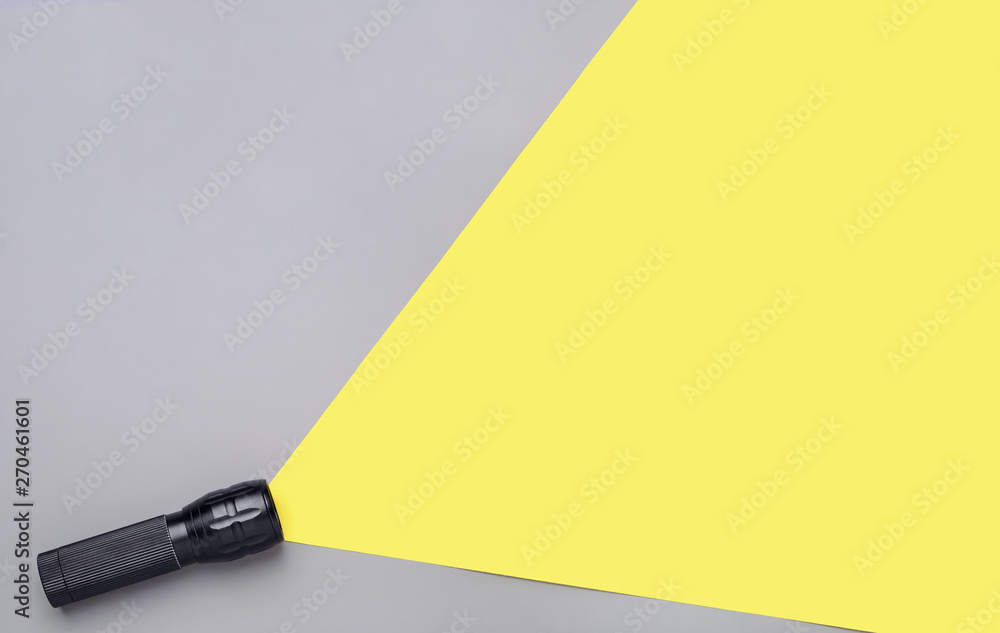 Flashlight turned on with yellow beam light on gray background with ...