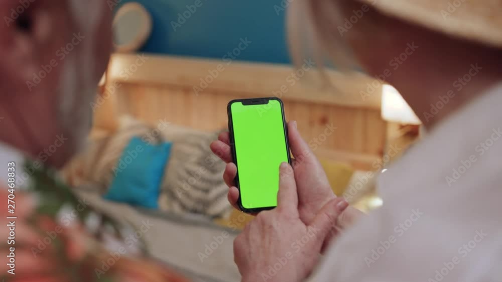 Back footage of two old persons. Elderly woman holding smartphone with ...