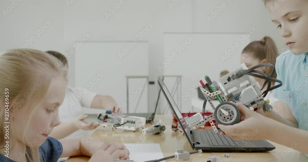 Curious kids working on a functional programable robot during robotics ...