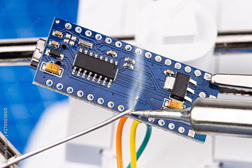 Soldering pins and wires with iron tool of blue micro controller chip ...
