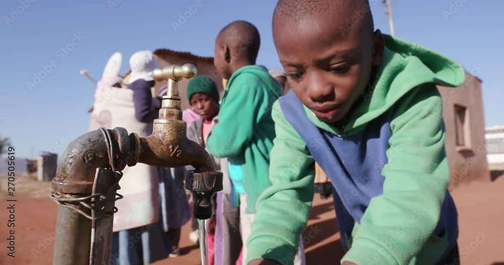 Water crisis.Young african boys drinking water from a tap while woman ...