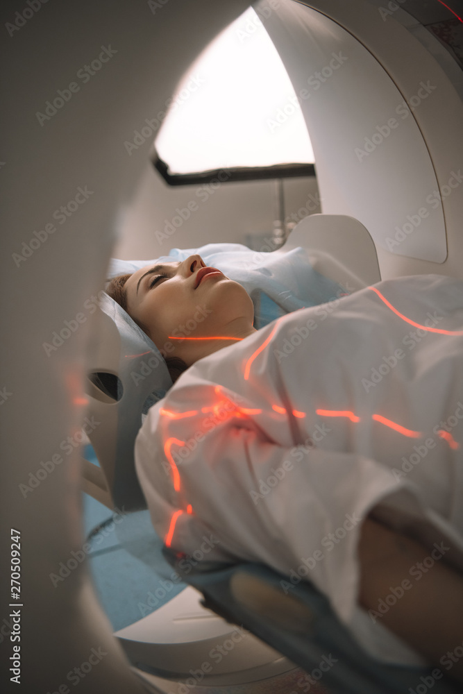 young woman lying on ct scanner bed during tomography diagnostics in ...