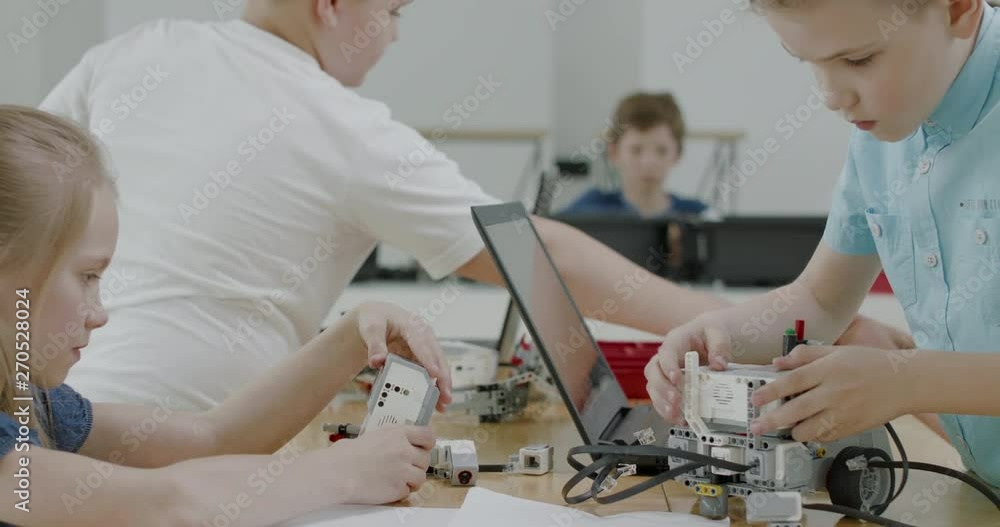 Curious kids working on a functional programable robot during robotics ...