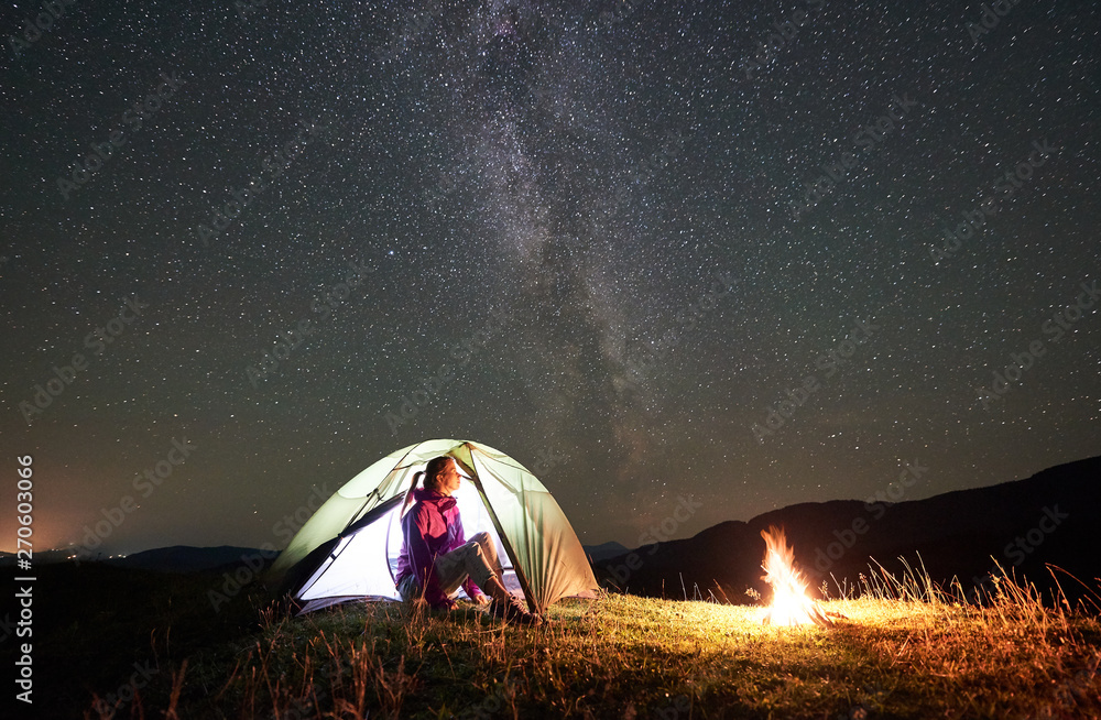 Female camper having a rest at summer night camping in the mountains ...