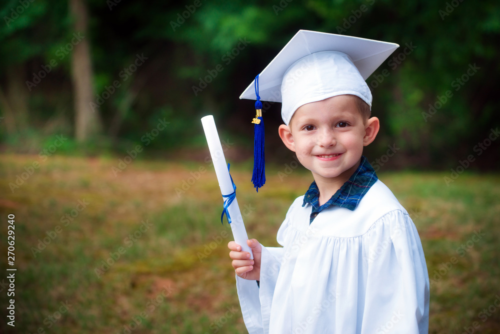 Cute Smiling Boy In Cap And Gown After Kindergarten Graduation Stock cute-smiling-boy-in-cap-and-gown-after-kindergarten-graduation-stock