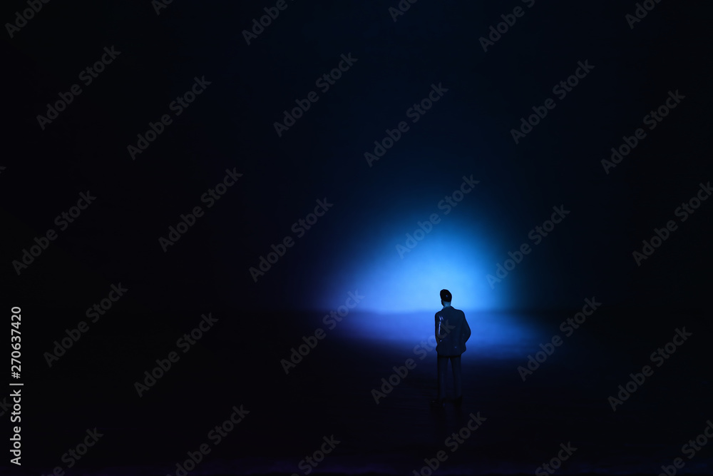 A picture of a miniature man stands in the spotlight looking forward ...