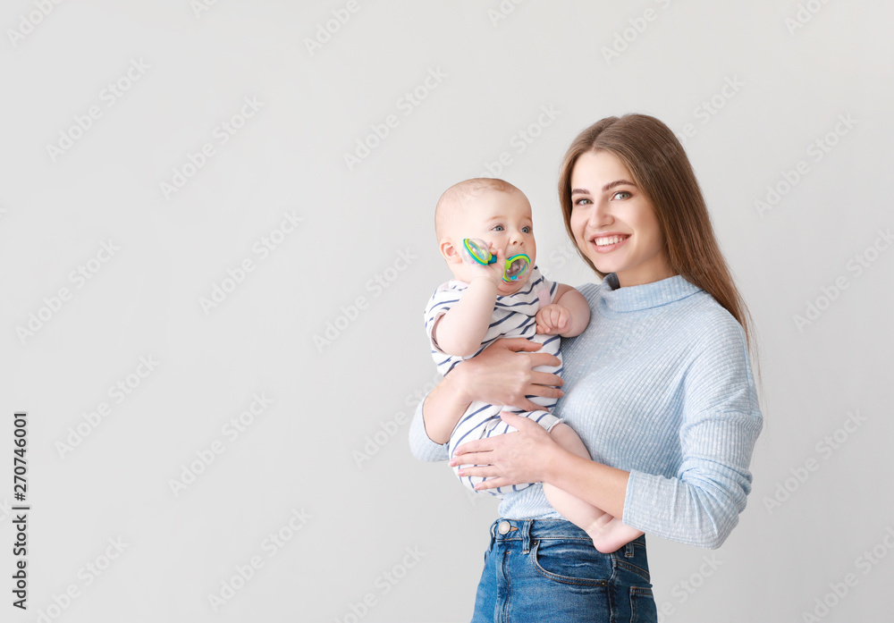 Happy mother with cute little baby on light background Stock Photo ...