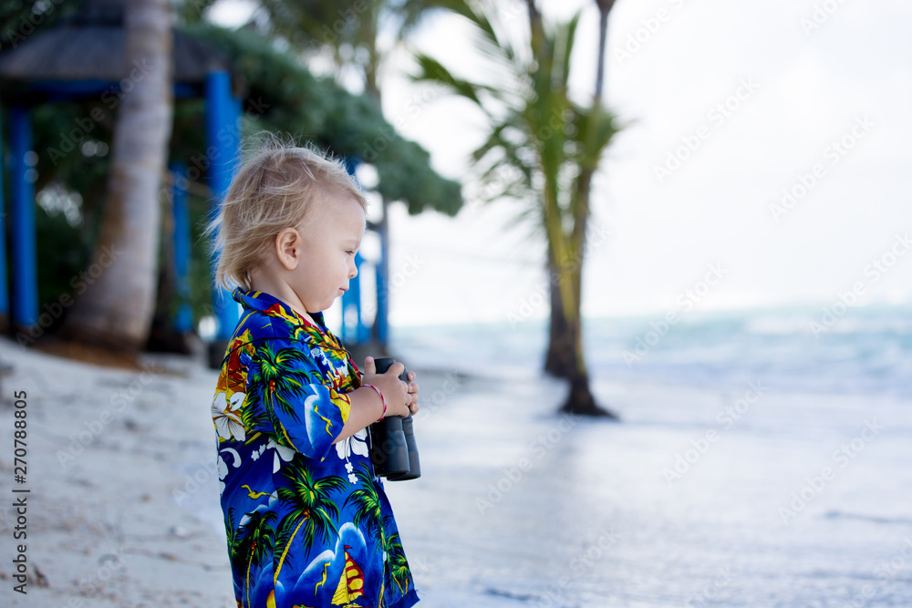Sweet boy looks through binoculars, observating the ocean life and ...