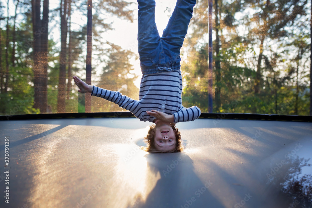 Foto de Sweet preteen boy jumping on trampoline making somersaults in ...