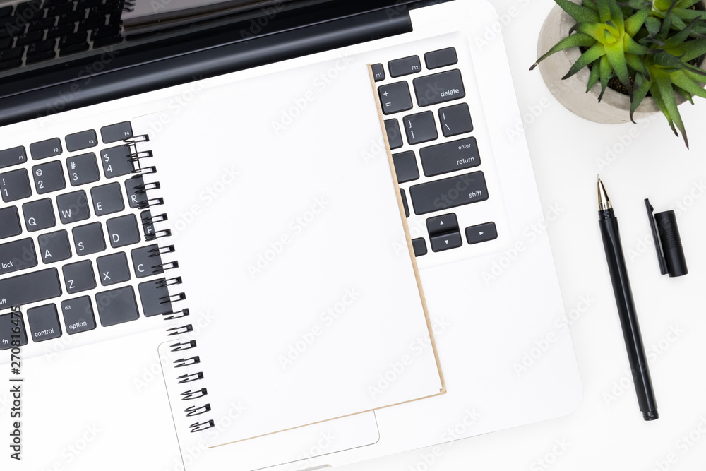 Blank notebok page with black pen is on top of laptop computer over ...