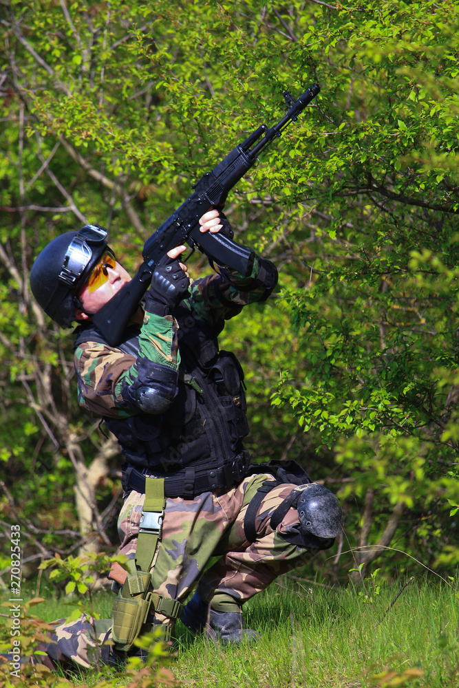 Commando with a rifle in his hand is shooting at an airborne target in ...