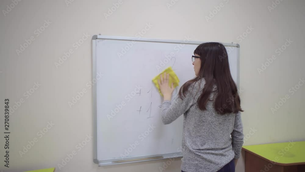 Female teacher stands at whiteboard and explains rules of addition in ...